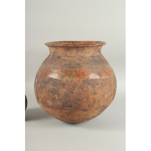 A LARGE AFRICAN BROWN POTTERY POT. 11ins and another pot, 5ins. (2)