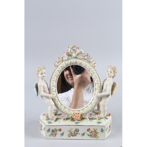 A DRESDEN DESIGN OVAL CUPID MIRROR encrusted with flowers. 11ins high.