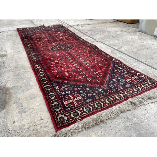 A SMALL RED PATTERNED FRINGED RUG