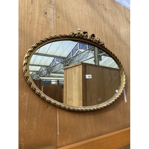 AN OVAL GILT FRAMED WALL MIRROR - 28 X 15 INCH