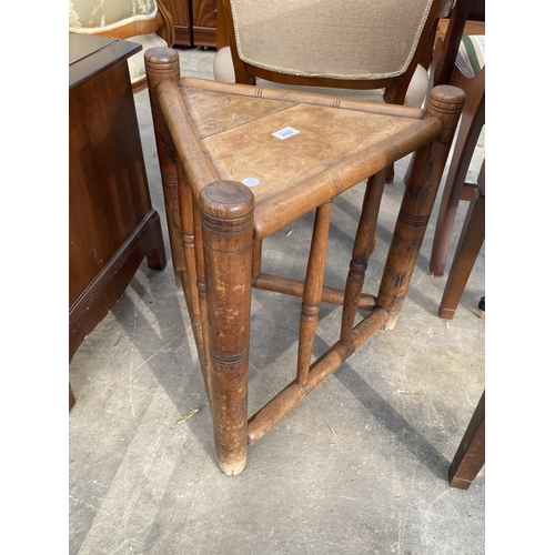 A THREE FOOTED TRIANGULAR SHAPED STOOL ON TURNED LEGS