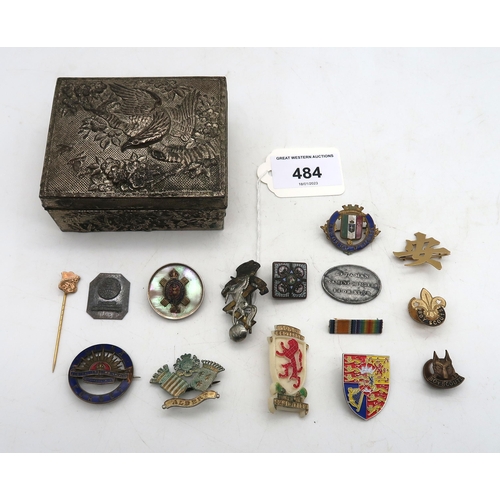 A small embossed white metal box containing a selection badges to ...