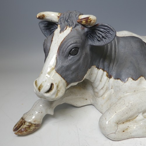 A very large pottery figure of a recumbent Cow, tail damaged and ...
