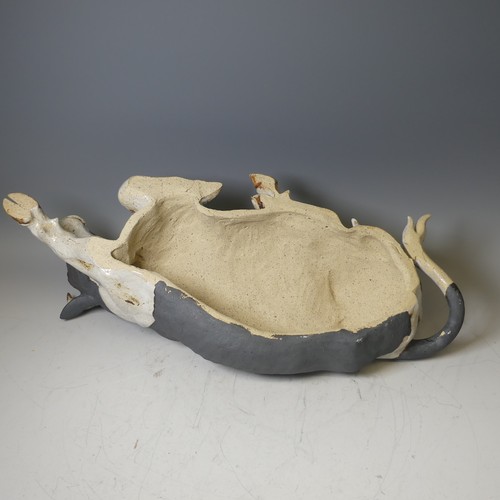 A very large pottery figure of a recumbent Cow, tail damaged and ...