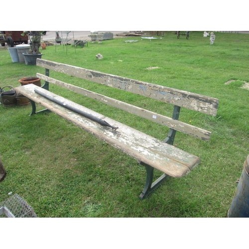 A wooden slatted railway station platform bench with cast ends