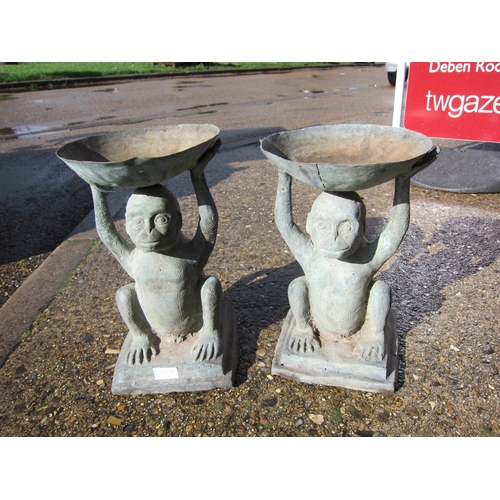 A pair of copper monkey finials, the monkey holding shallow dishes ...