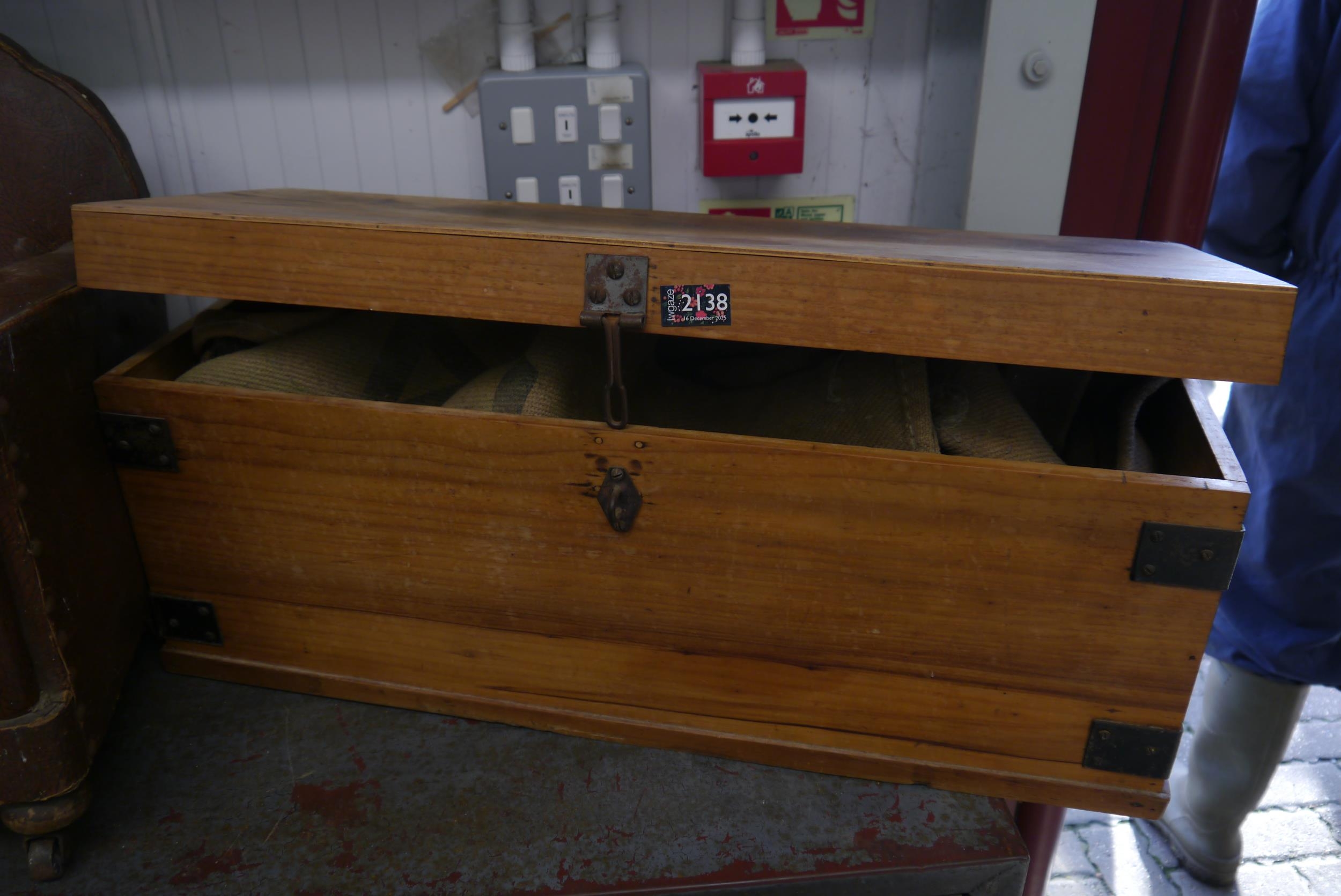 A pine box with metal mounts containing hessian sacks