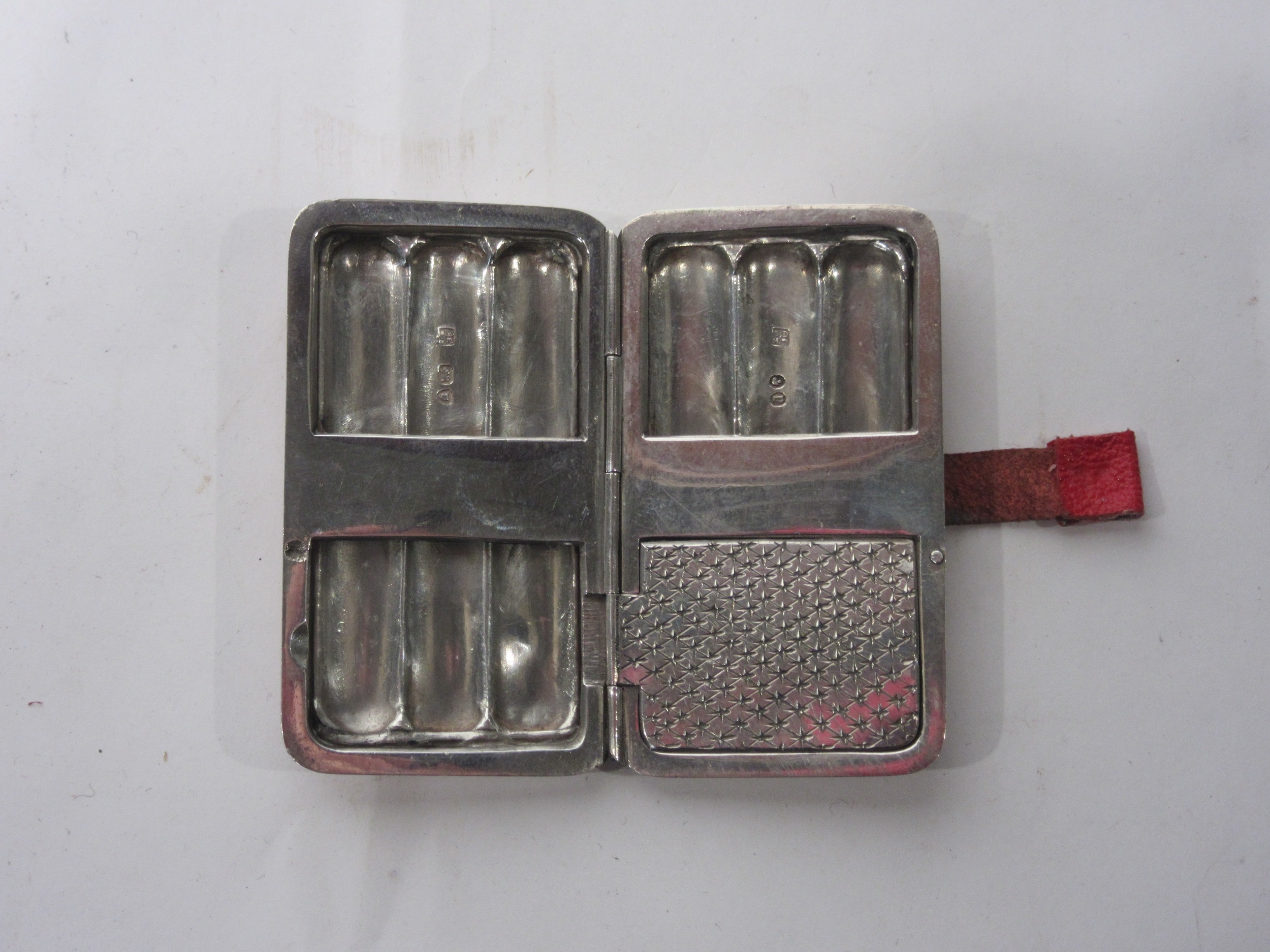 A silver lady's cigarette case with red leather exterior