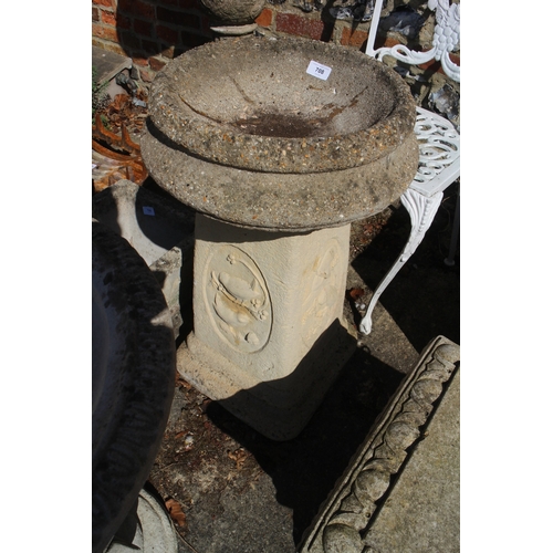 A cast stone bird bath with relief plaques decorated with birds
