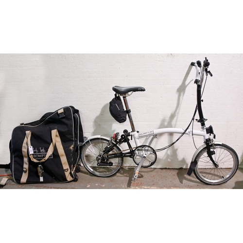 A Brompton folding bicycle, white, with bag
