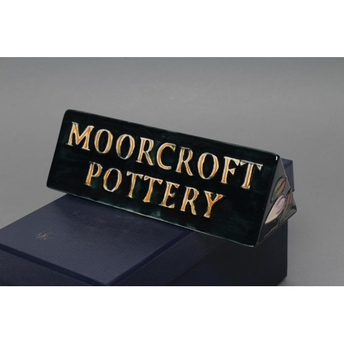 A MOORCROFT POTTERY SIGN, 2002, of triangular section, one side moulded ...