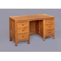 A ROBERT THOMPSON ADZED OAK PEDESTAL DESK, the moulded edge and canted ...