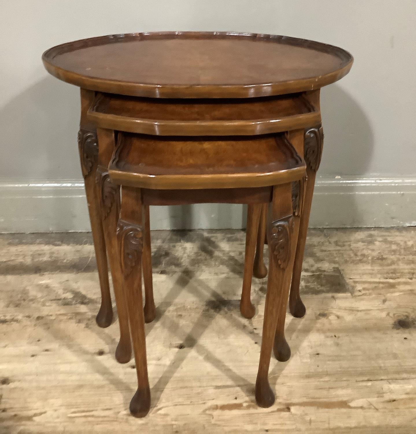A nest of figured walnut occasional tables of oval outline on foliate carved legs