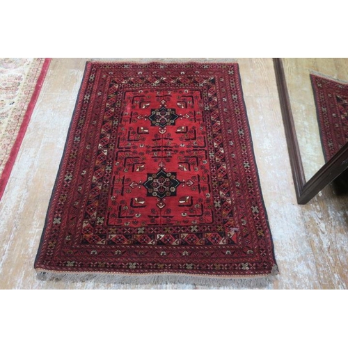 AN ORIENTAL WOOL RUG the light wine ground with central panel filled ...
