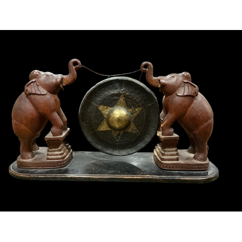 AN ORIENTAL BRASS AND CARVED WOOD DINNER GONG the circular dish shaped ...