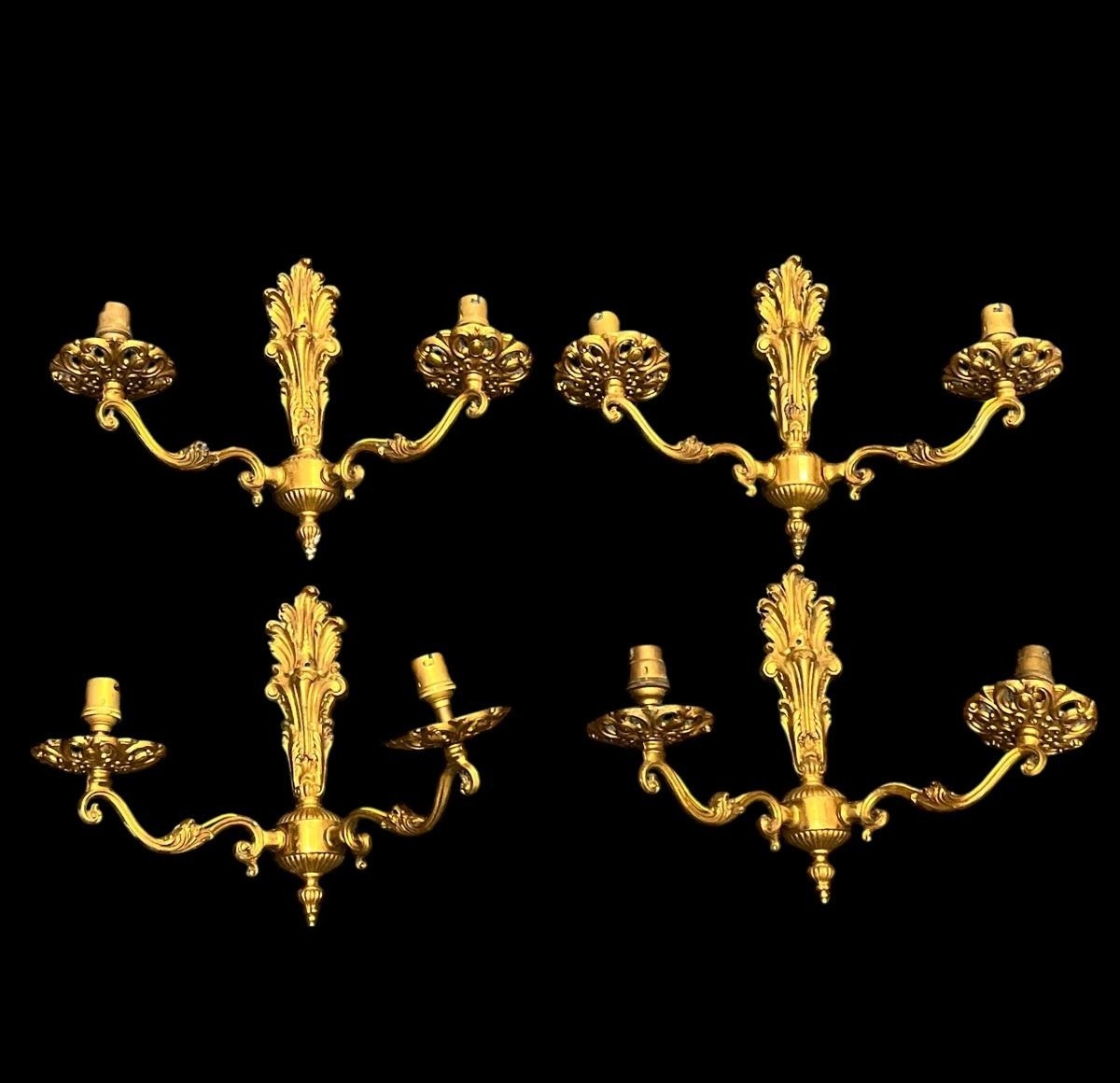 A SET OF FOUR BRASS TWO BRANCH WALL SCONCES the foliate cast back plate ...