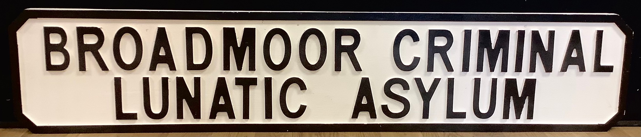 A decorative wooden sign, 'BROADMOOR CRIMINAL LUNATIC ASYLUM'