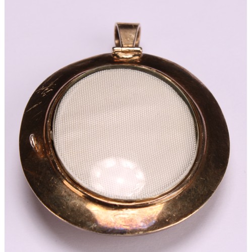 A Victorian gold coloured metal oval pendant, engraved with scrolls and ...