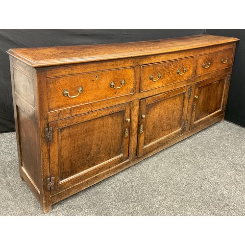 A George III oak low dresser, moulded oversailing top above three deep ...