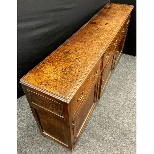 A George III oak low dresser, moulded oversailing top above three deep ...