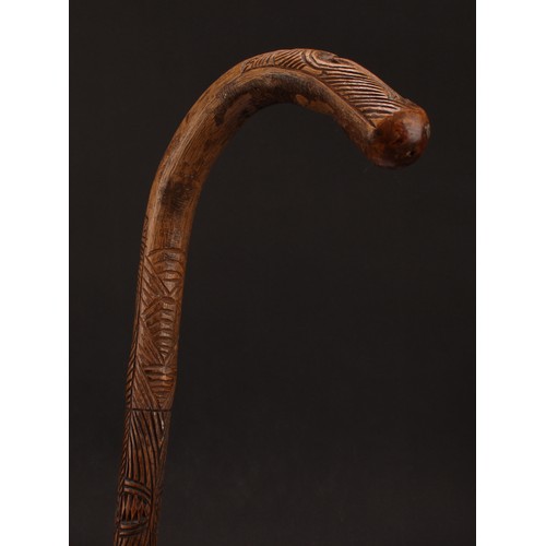 A Maori walking stick, carved with teke masks and geometric tribal ...