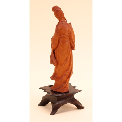 A Japanese hardwood figure on stand, carved as a Geisha, she stands ...