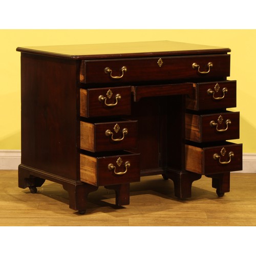 An early George III mahogany kneehole desk, oversailing top with ...