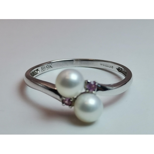 A 9 carat white gold pearl cross-over ring, set with two small round ...