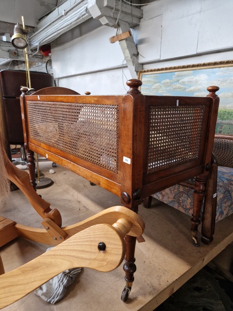 A Victorian mahogany cot with canework sides.