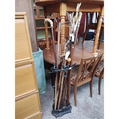 A cast iron stick stand with various sticks including horn handles, etc.