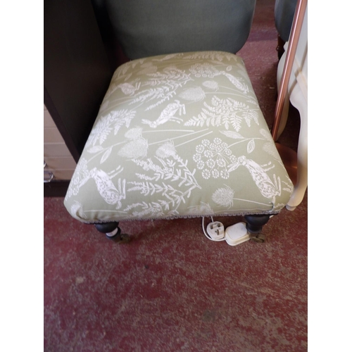 A rectangular footstool upholstered in green coloured patterned fabric