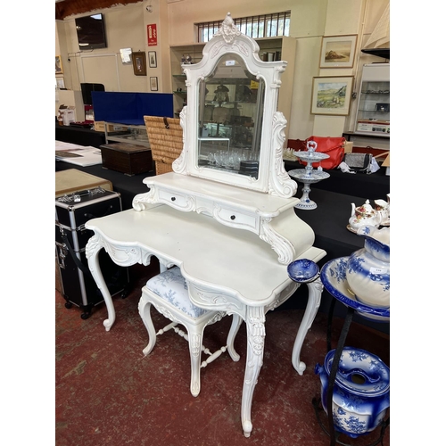 An ornate dressing table and stool finished in a distressed white
