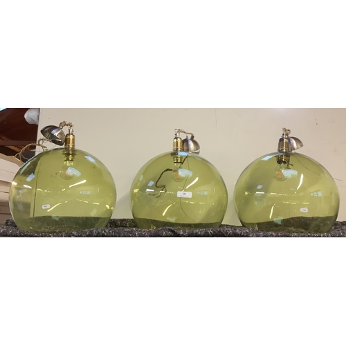 A set of three contemporary green glass light fittings of spherical form