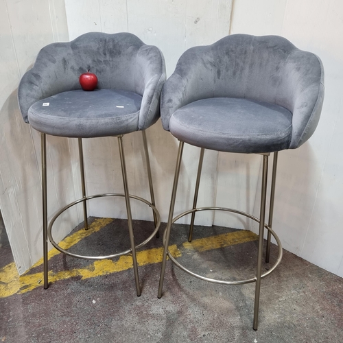 A pair of stylish bar stools with a plush grey upholstery and a scallop ...