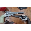 Two replica revolvers with ornate engraving and holsters.