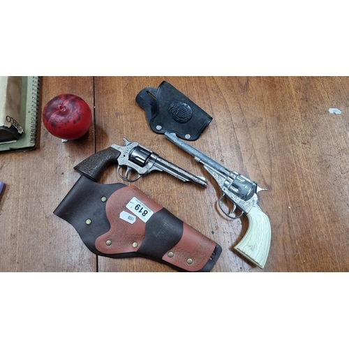 Two replica revolvers with ornate engraving and holsters.