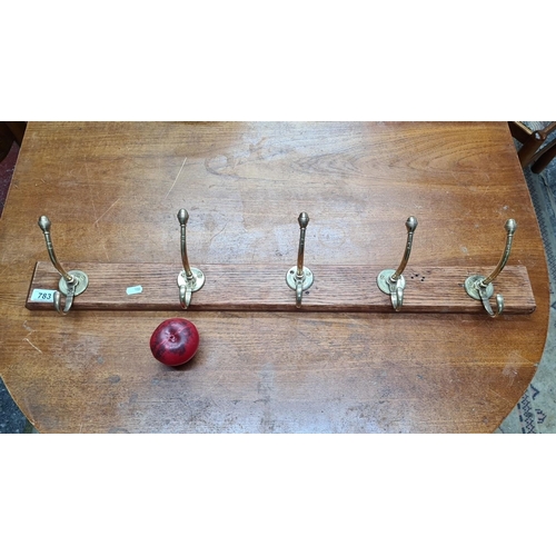 A lovely vintage wooden coat rack with five brass hooks, displaying a ...