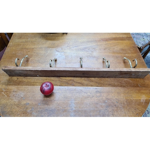 A lovely vintage wooden coat rack with five brass hooks, displaying a ...