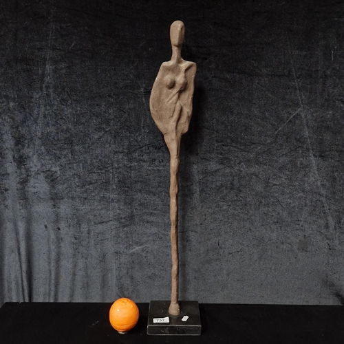 An abstract metal figural sculpture of a tall slender woman on one ...