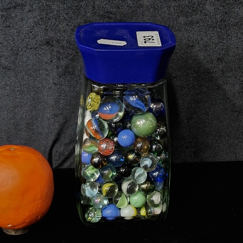 A jar containing a large selection of colourful marbles in various ...
