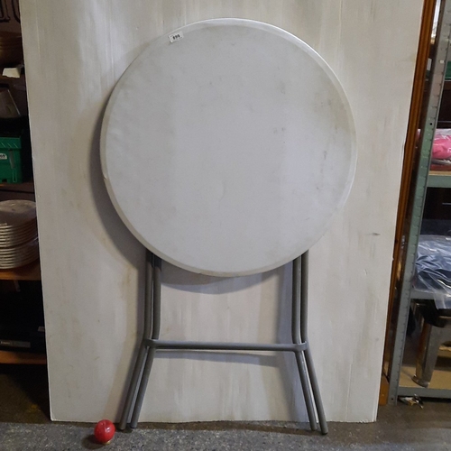 One circular folding table with white laminate top and grey tubular ...