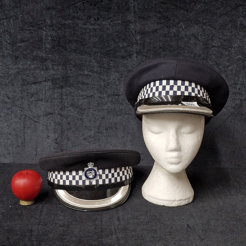 Two Staffordshire police peaked caps. Holding wool navy-blue cap ...