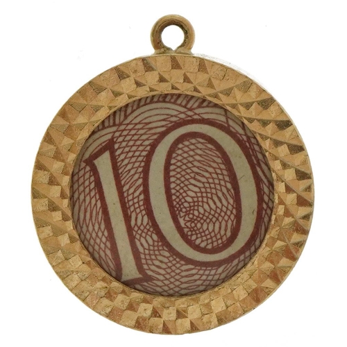 9ct gold emergency ten shilling note charm, 1.8cm in diameter, 3.5g