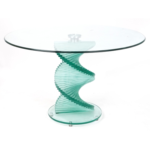 A contemporary circular glass dining table raised on a stepped glass ...