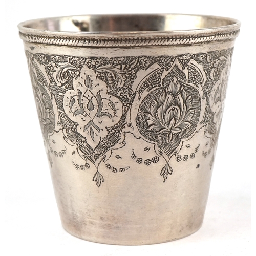An Islamic silver beaker profusely engraved with scrolling floral ...