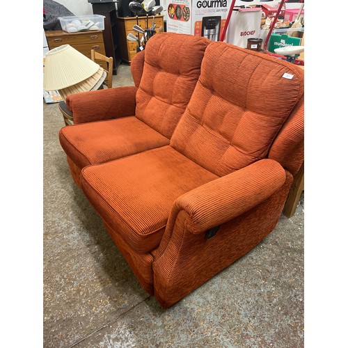 Two seater sofa in burnt orange cord fabric - one half reclines - splits into 2 units