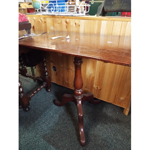 A mahogany oblong snap top side table resting on tri-form base