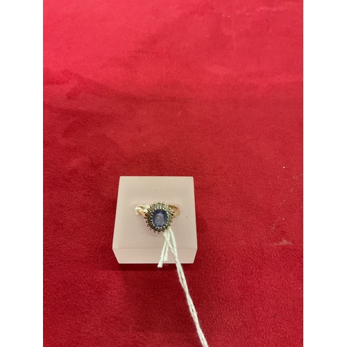 A 9ct gold cluster ring inset with oval sapphire flanked by diamonds ...