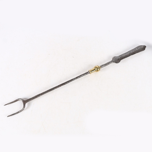 A MID-18TH CENTURY IRON AND BRASS MEAT FORK, ENGLISH, CIRCA 1750. With two tines, the stem flattenin