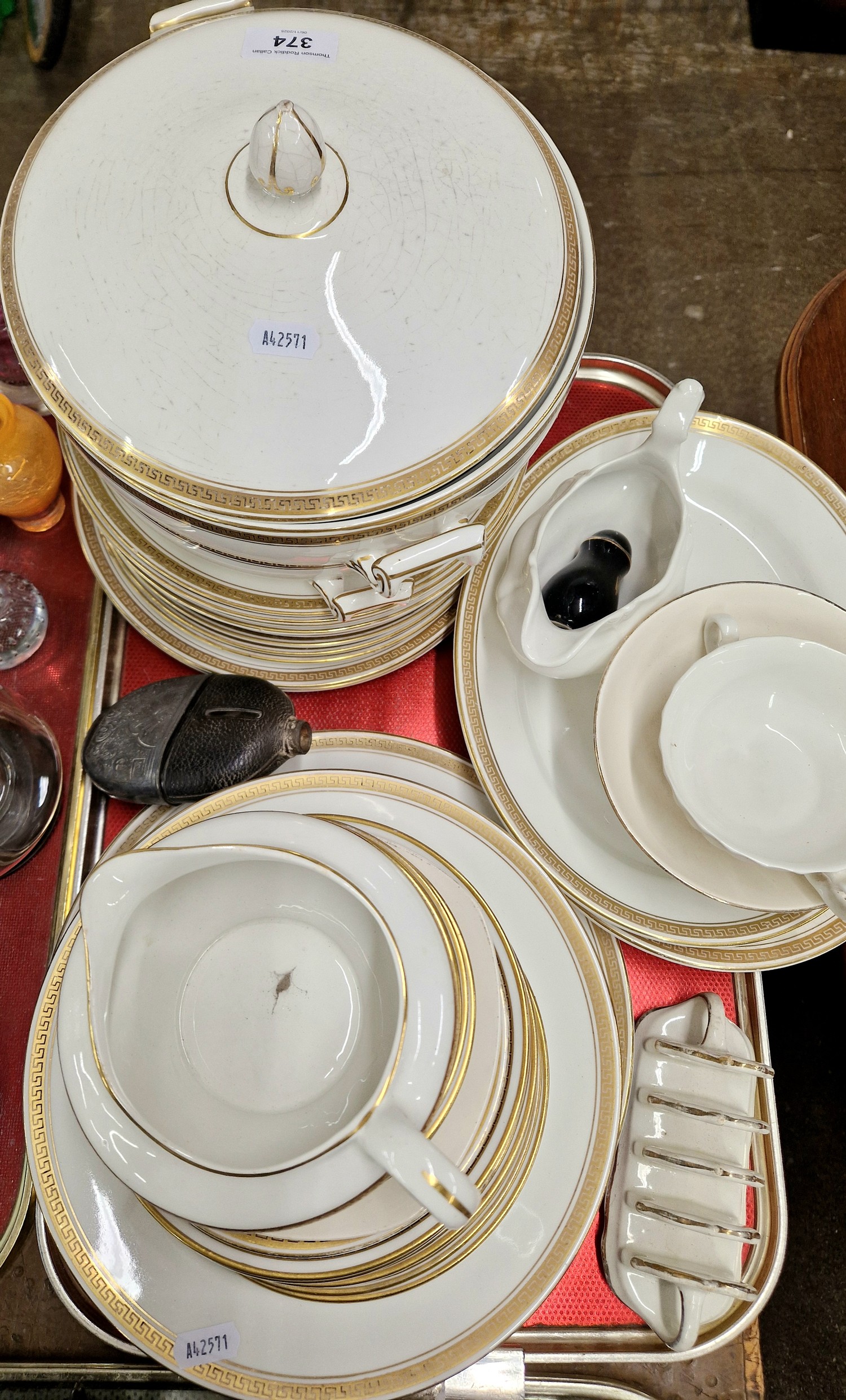 Gold and white patterned dinner service with Greek key design.